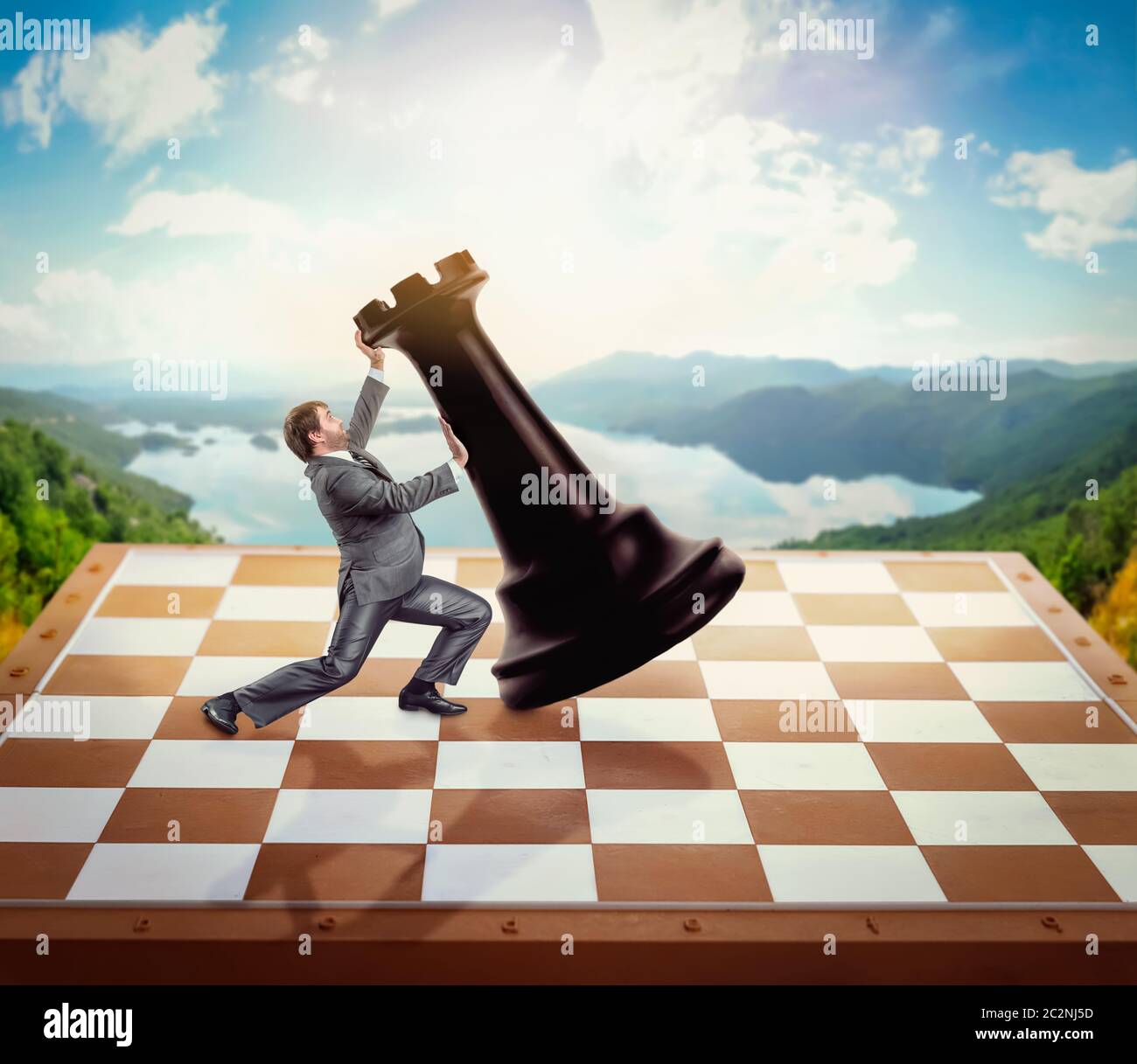 Businessman fighting with a chessman on chess board over nature ...