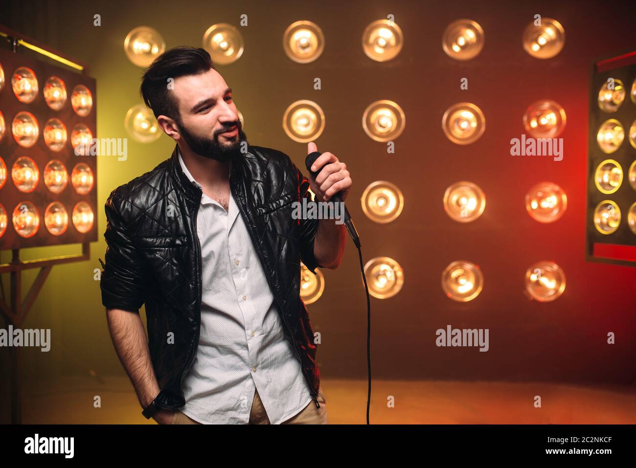 Brutal bearded singer with microphone on the stage with the decorations ...