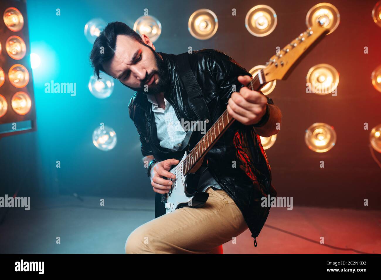 Male solo musican with electro guitar on the stage with the decorations ...