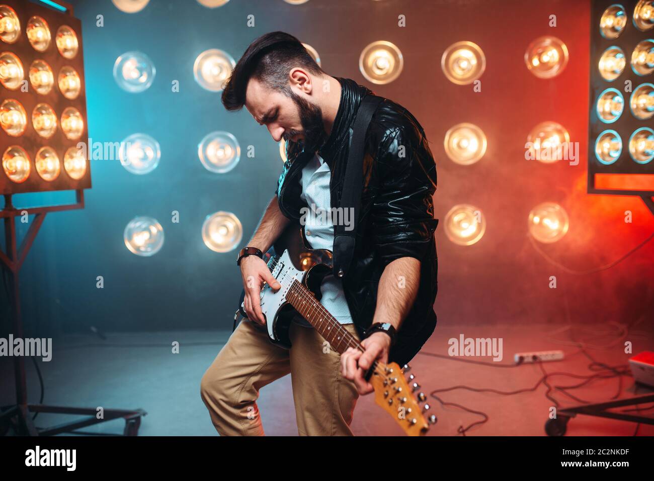 Male solo musican with electro guitar on the stage with the decorations ...