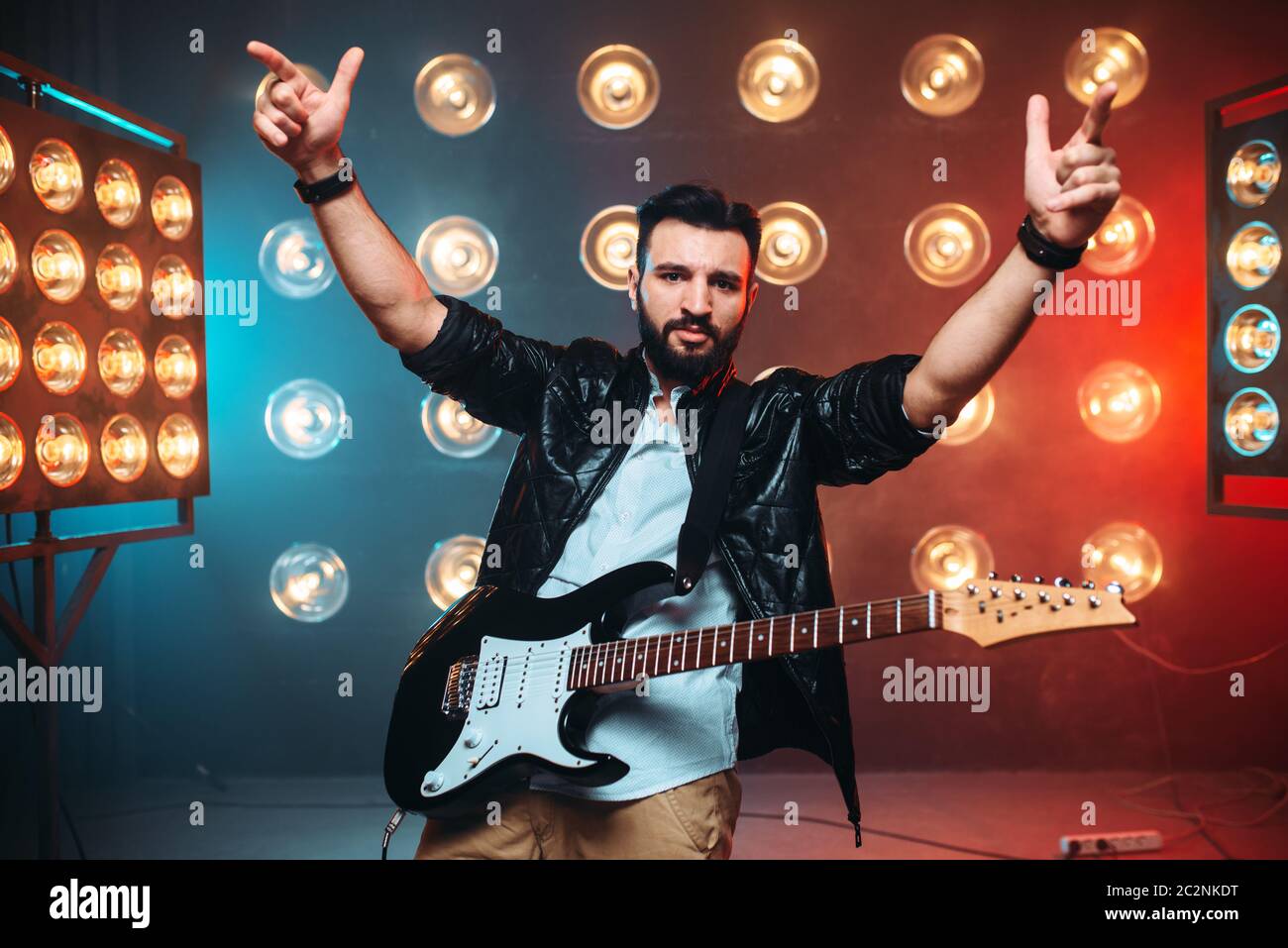 Male solo musican with electro guitar on the stage with the decorations ...