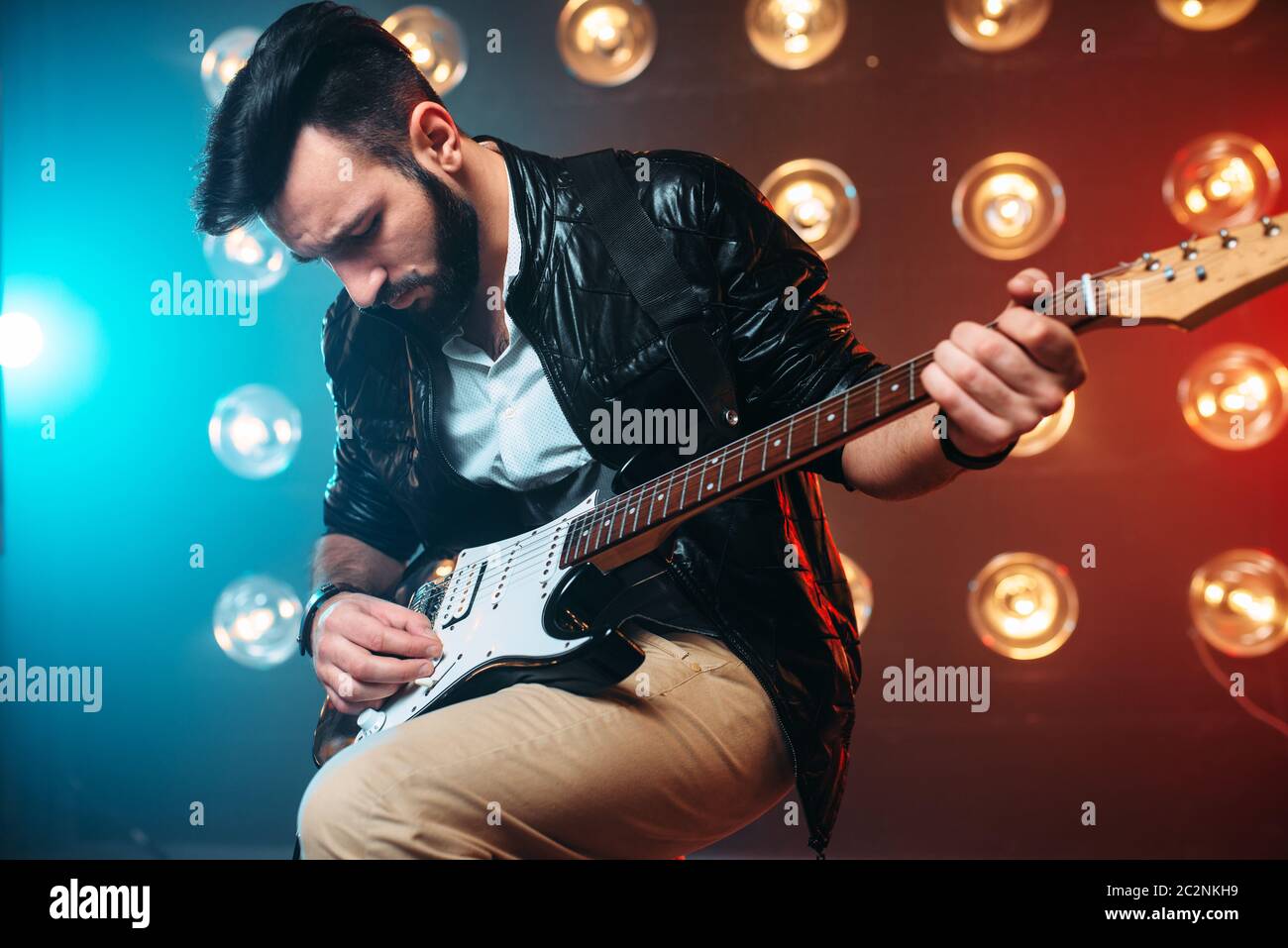 Male solo musican with electro guitar on the stage with the decorations ...