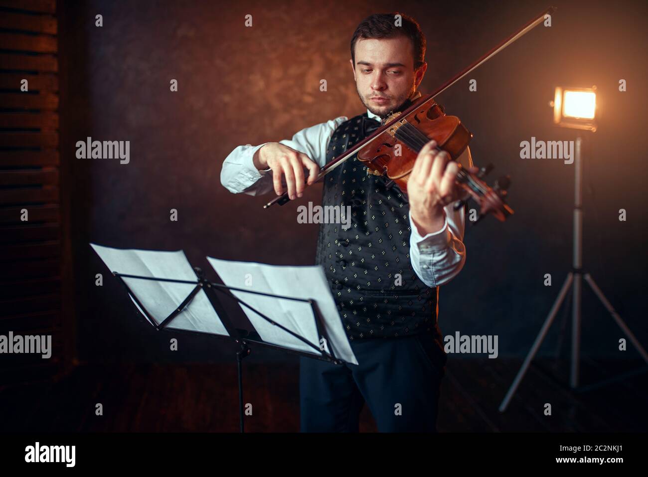 Portrait of male violinist with violin against music stand. Fiddler man ...