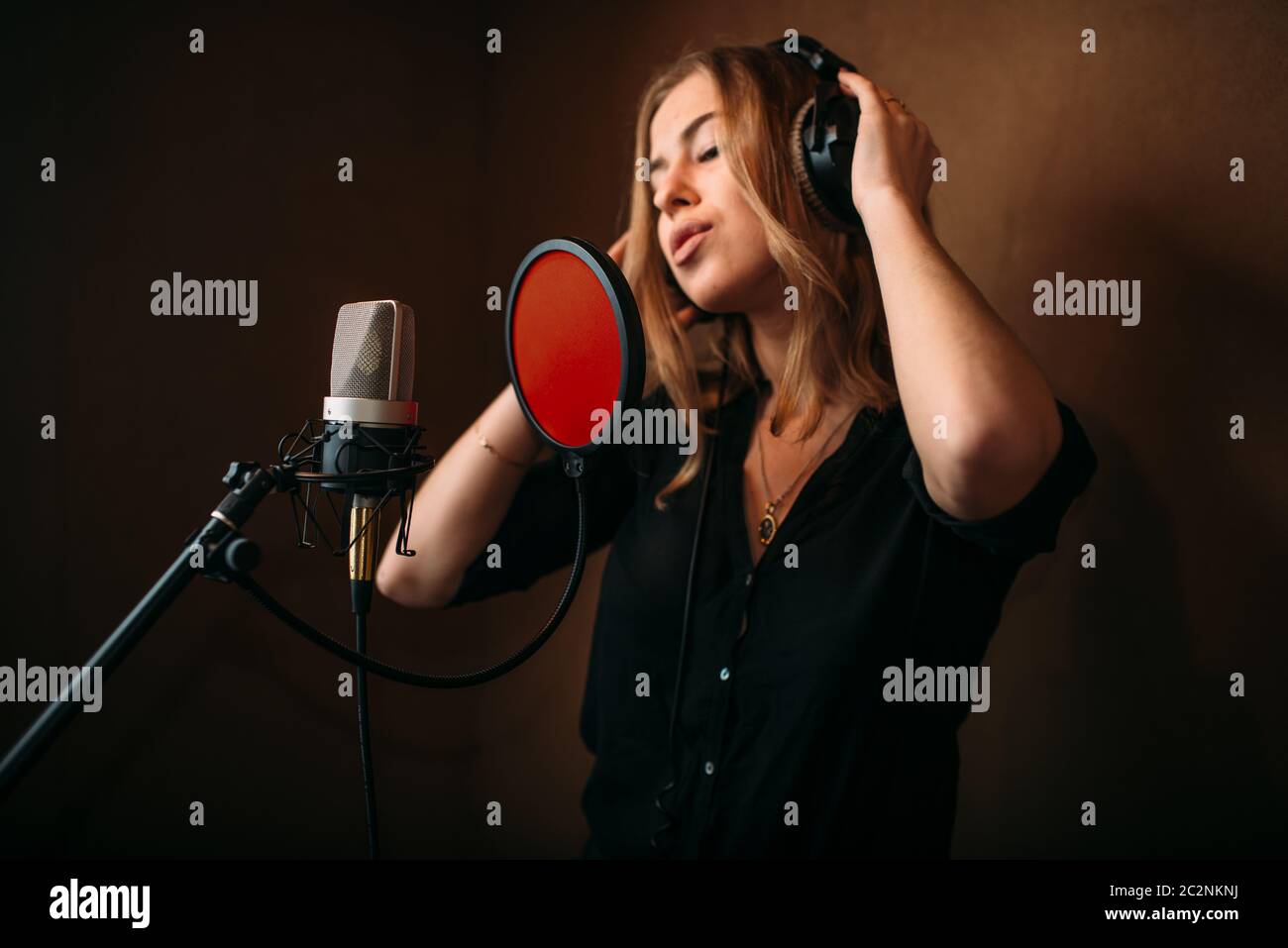 Female singer in headphones against microphone, song record in music ...
