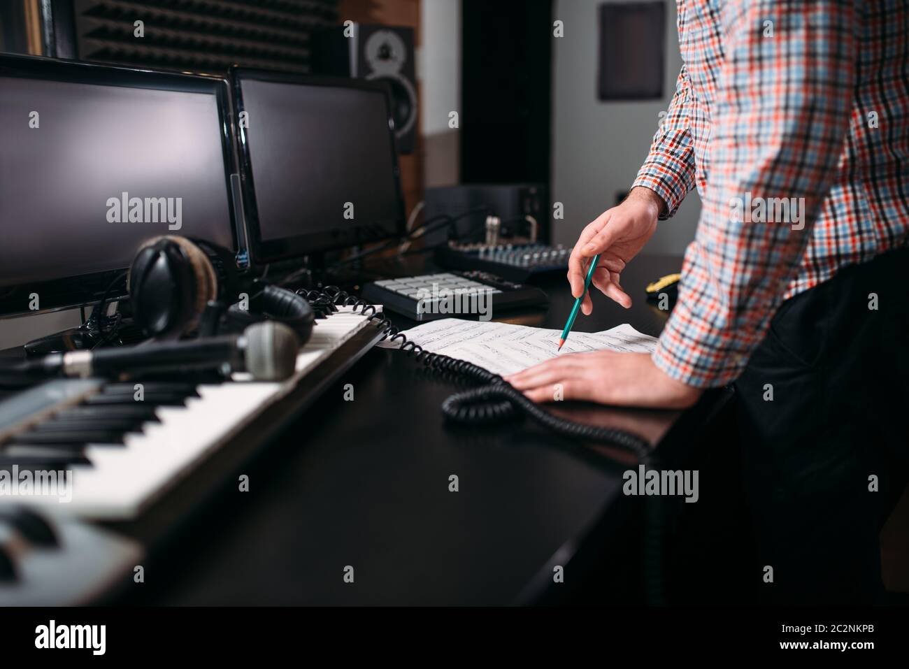 Male sound engineer hands on the table, musical keyboard, microphone ...