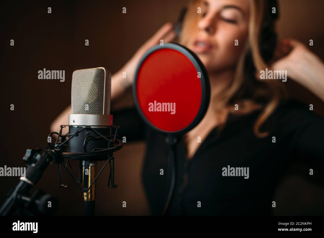 Female singer in headphones against microphone, song record in music ...
