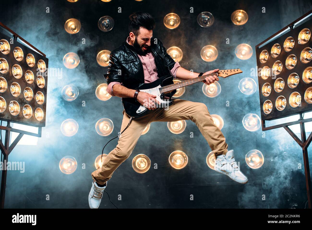 Male pop star with electro guitar on the stage with the decorations of ...
