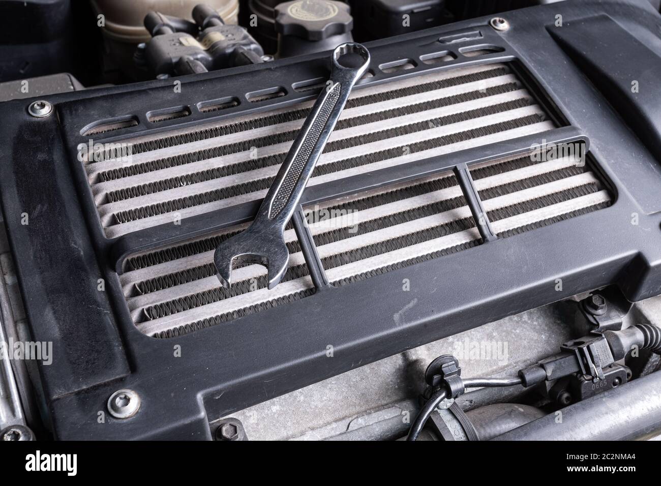 A metal spanner under the hood of the car on an oil cooler. Concept of ...