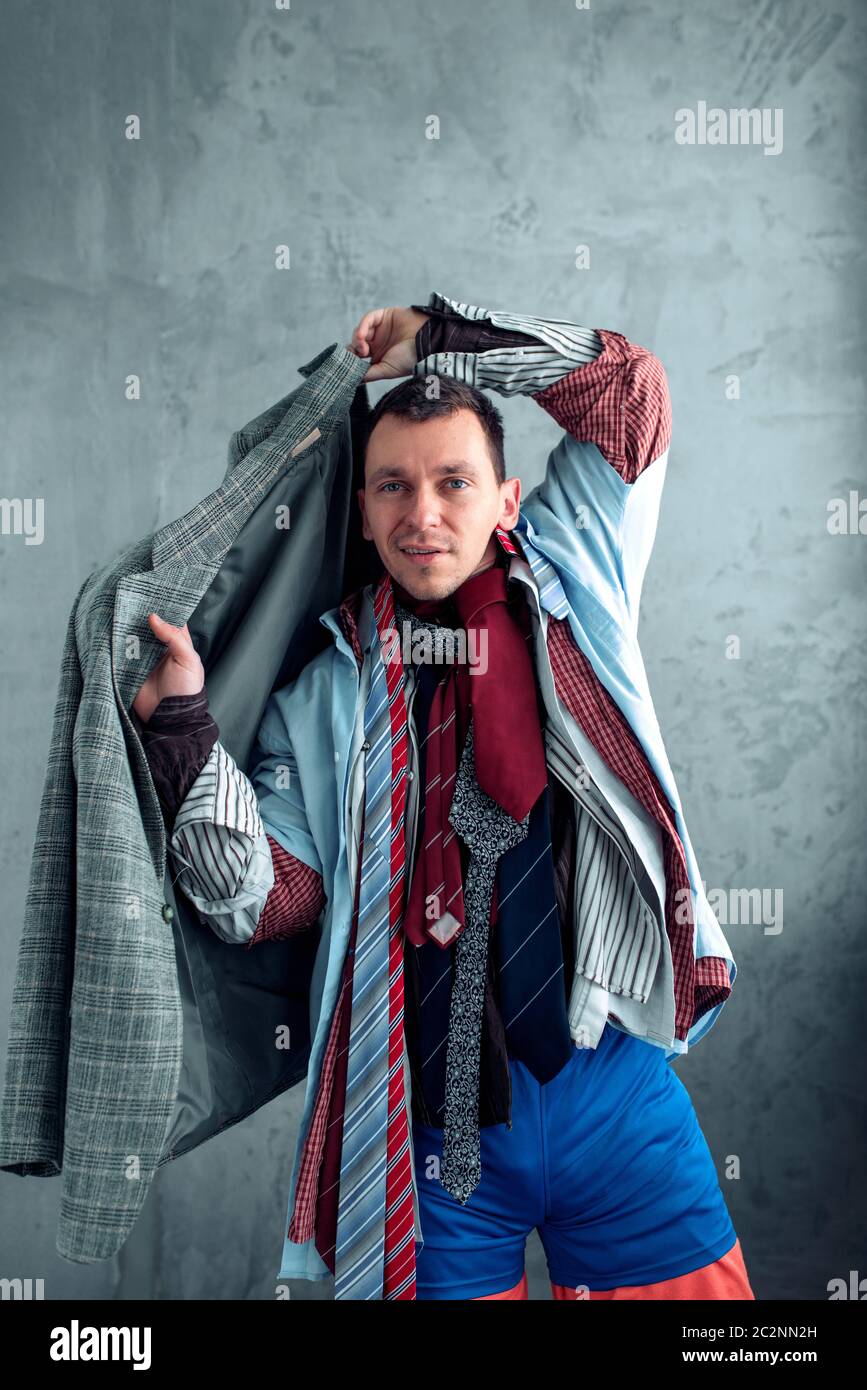 Man dressed in many clothes trying on a jacket at the clothing store ...