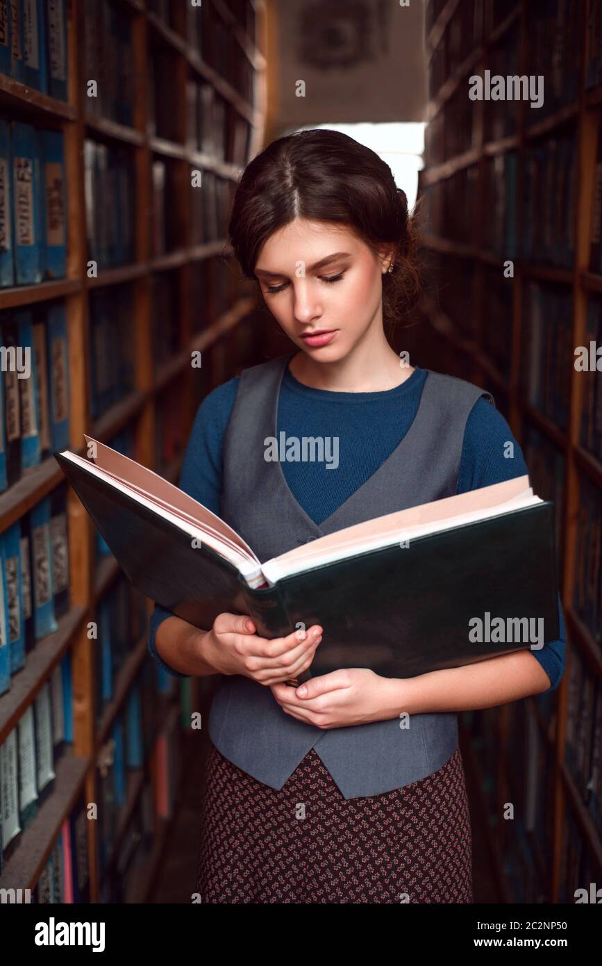 Portrait of serious student with open book reading it in college ...