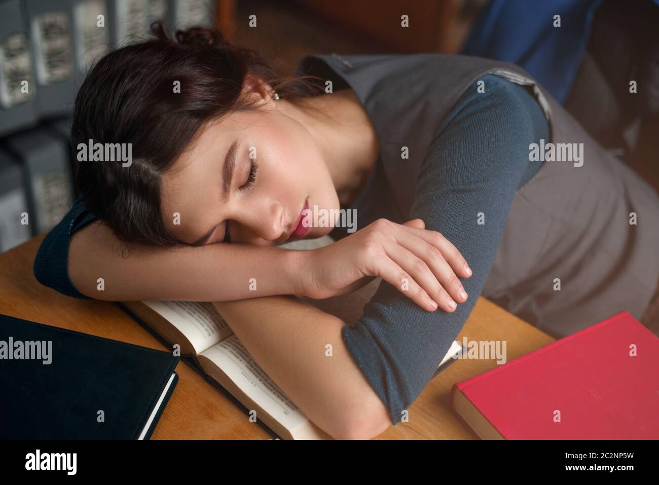 Young girl fell asleep while reading a book in college library ...