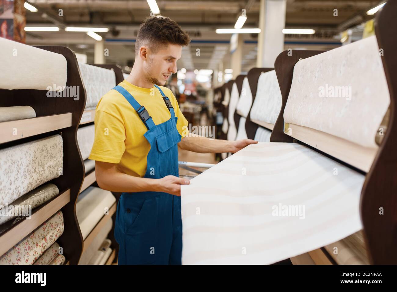Male builder choosing wallpapers in hardware store. Constructor in ...