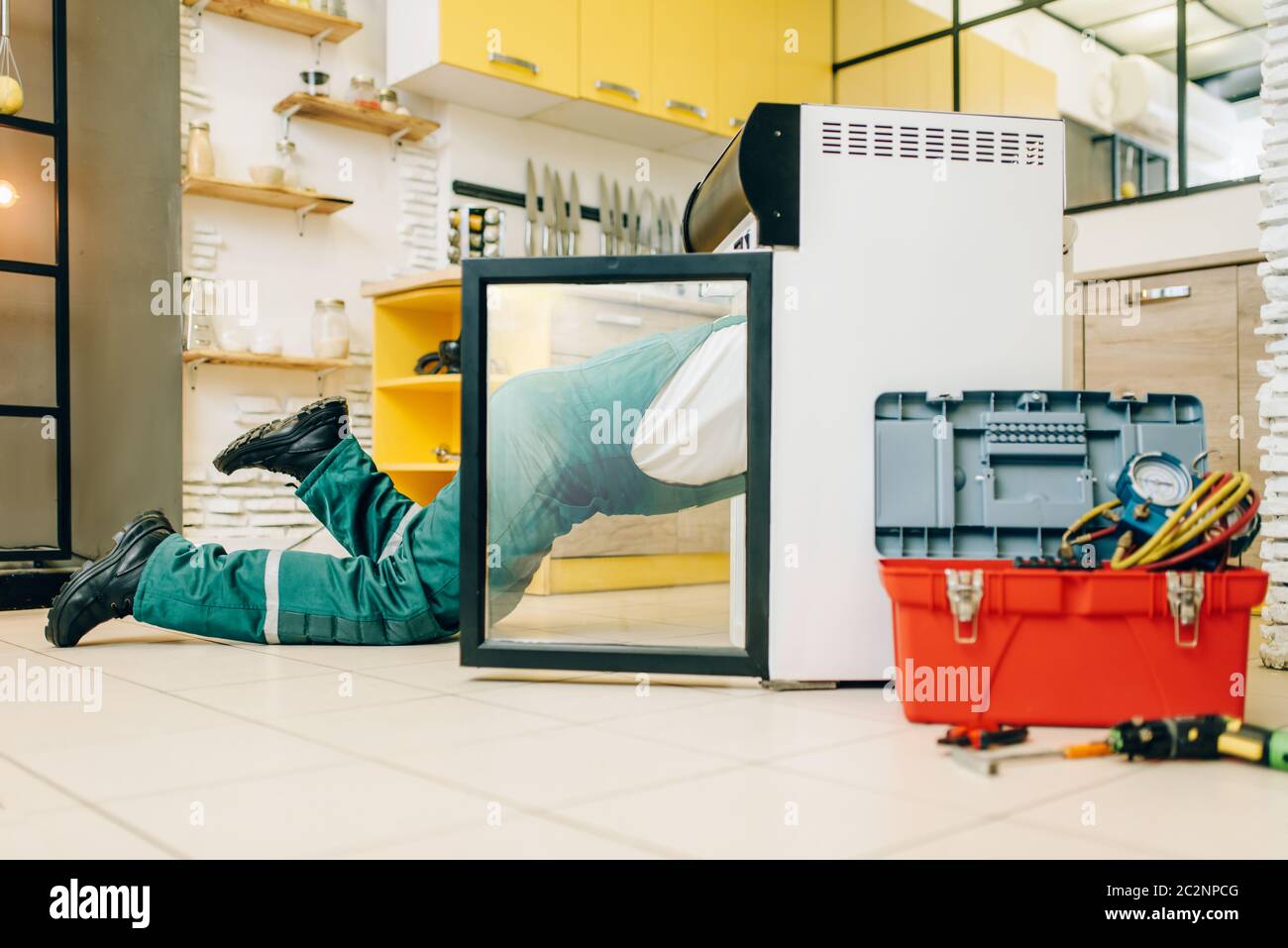 Worker in uniform climbed inside the refrigerator at home. Repairing of ...