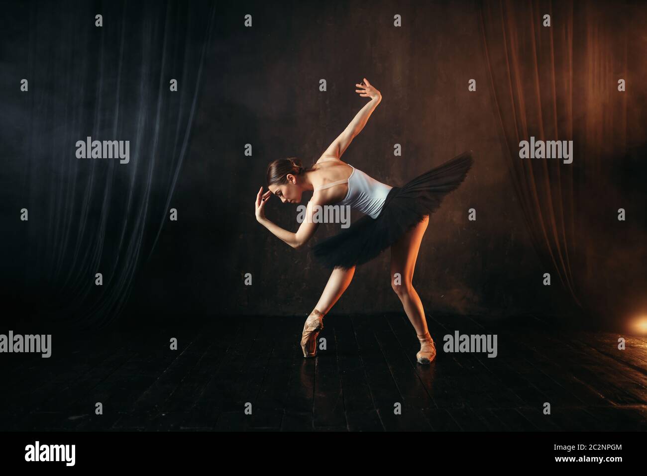 Attractive ballerina in action, dance training on the stage. Classical ...