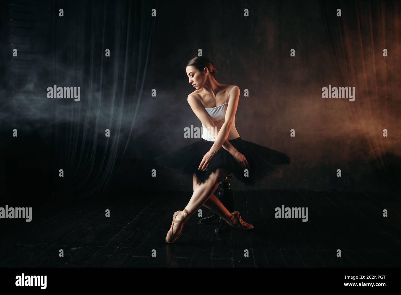 Ballet dancer sitting on black banquette on the stage in theatre ...