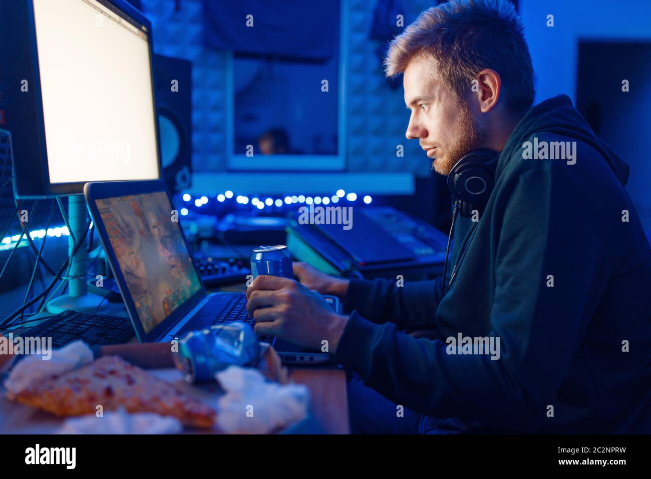 Male gamer drinking an energy drink at his workplace with laptop and ...