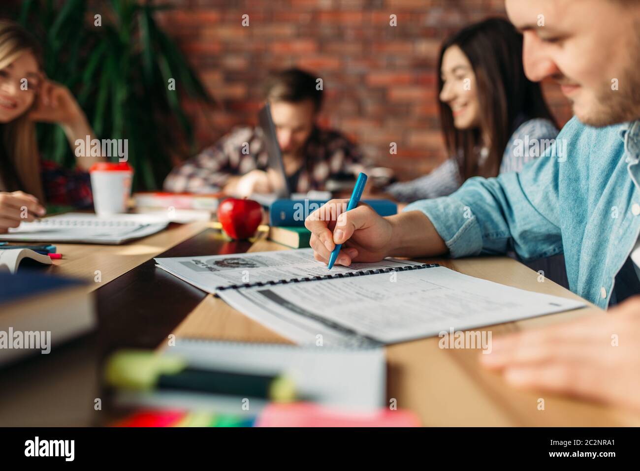 Group of students studying at the table together Stock Photo - Alamy