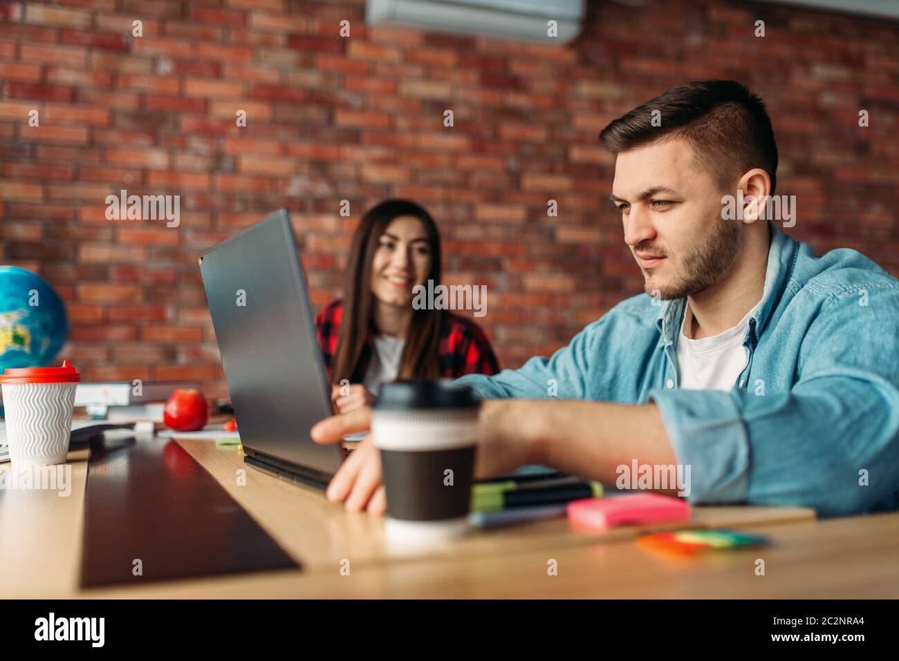 Students with computer studying at the table together. People with ...