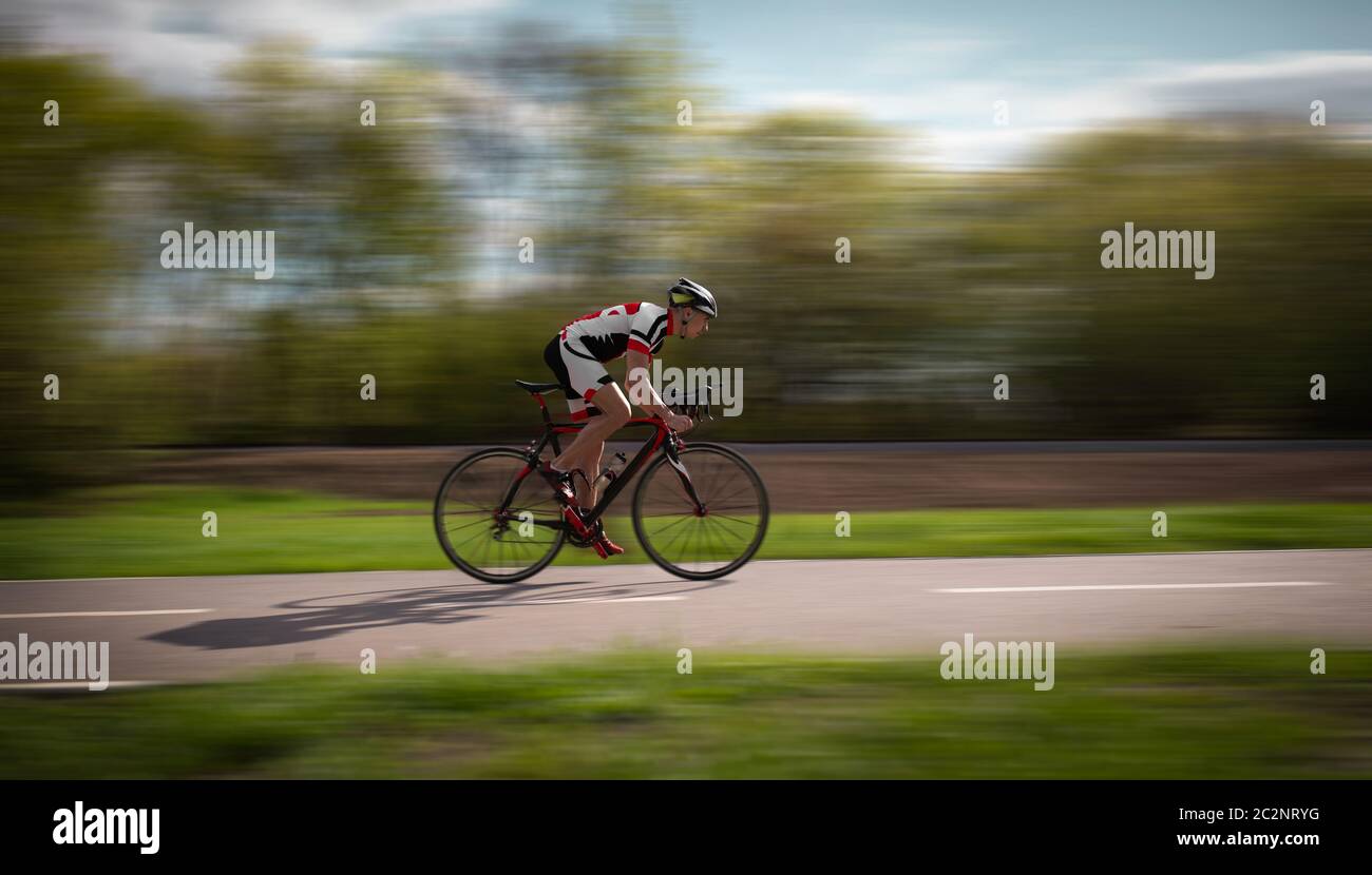 Cyclist in helmet and sportswear rides on bicycle, speed effect, side ...