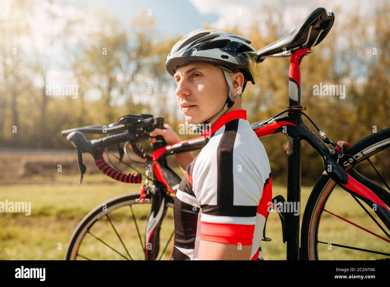 Cyclist in helmet and sportswear keeps the bike on shoulder, cycling on ...