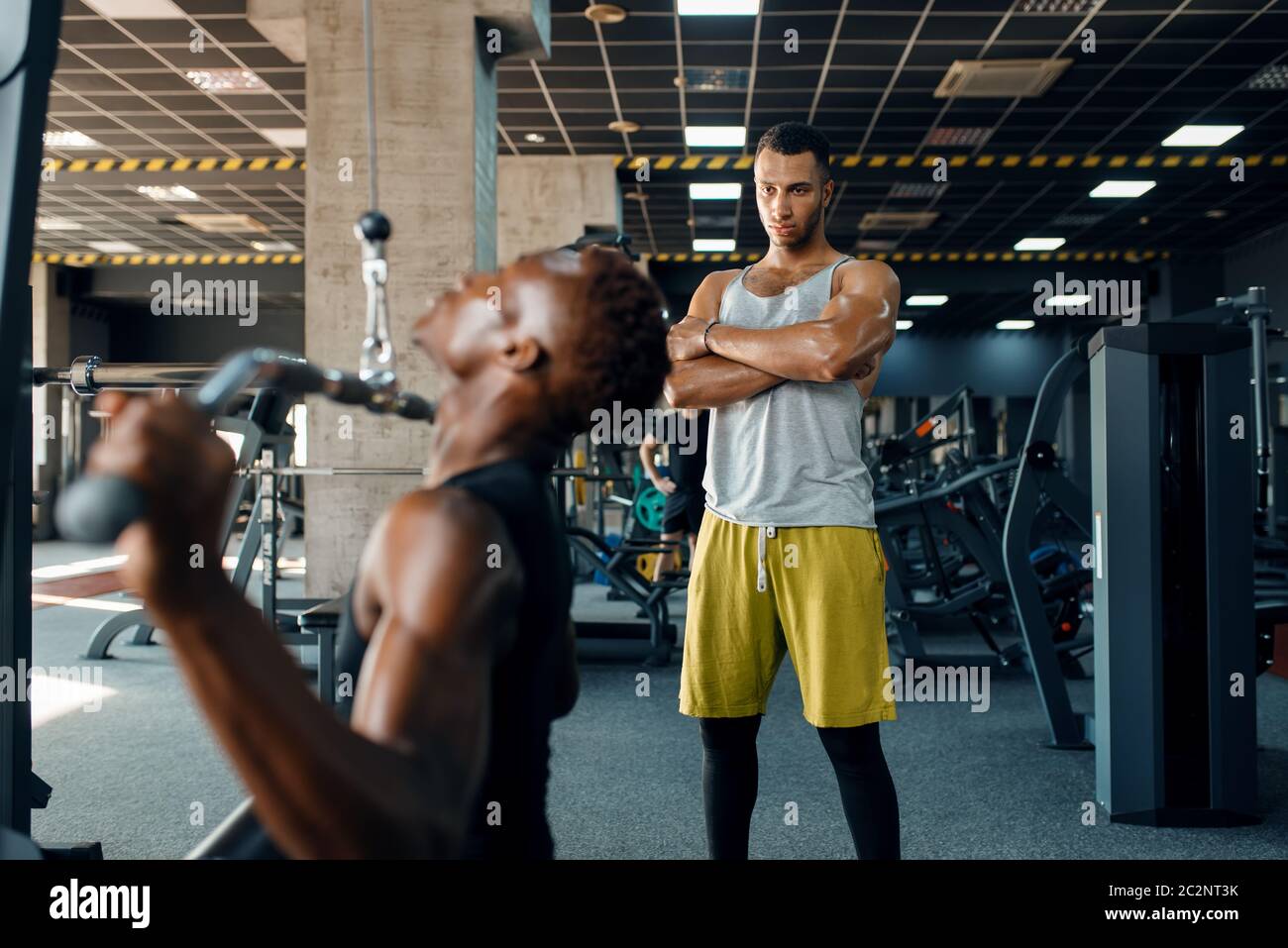 Muscular man and his instructor, exercise with barbell on training in ...