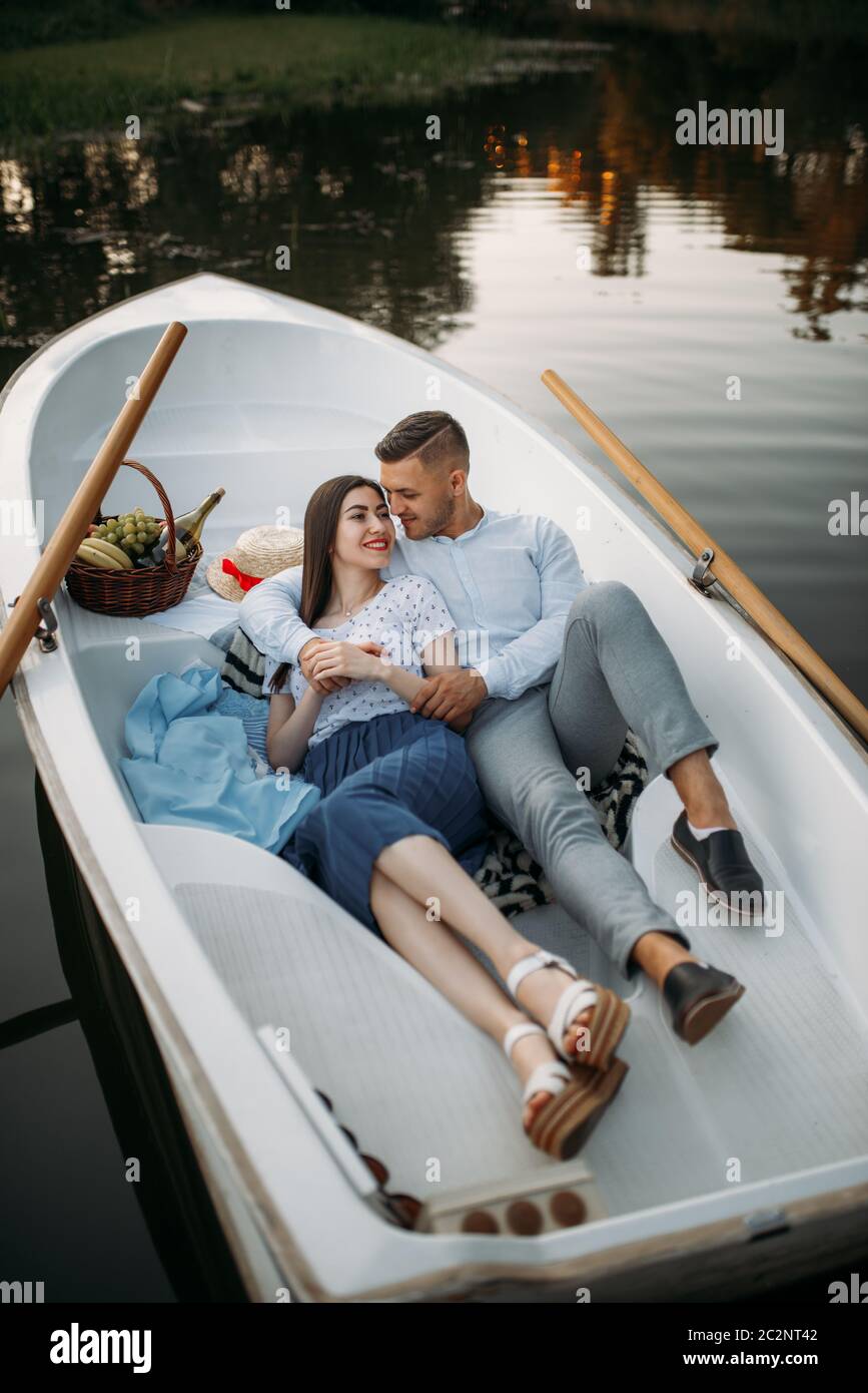 Love couple lying in a boat on quiet lake and dreaming at sunset ...