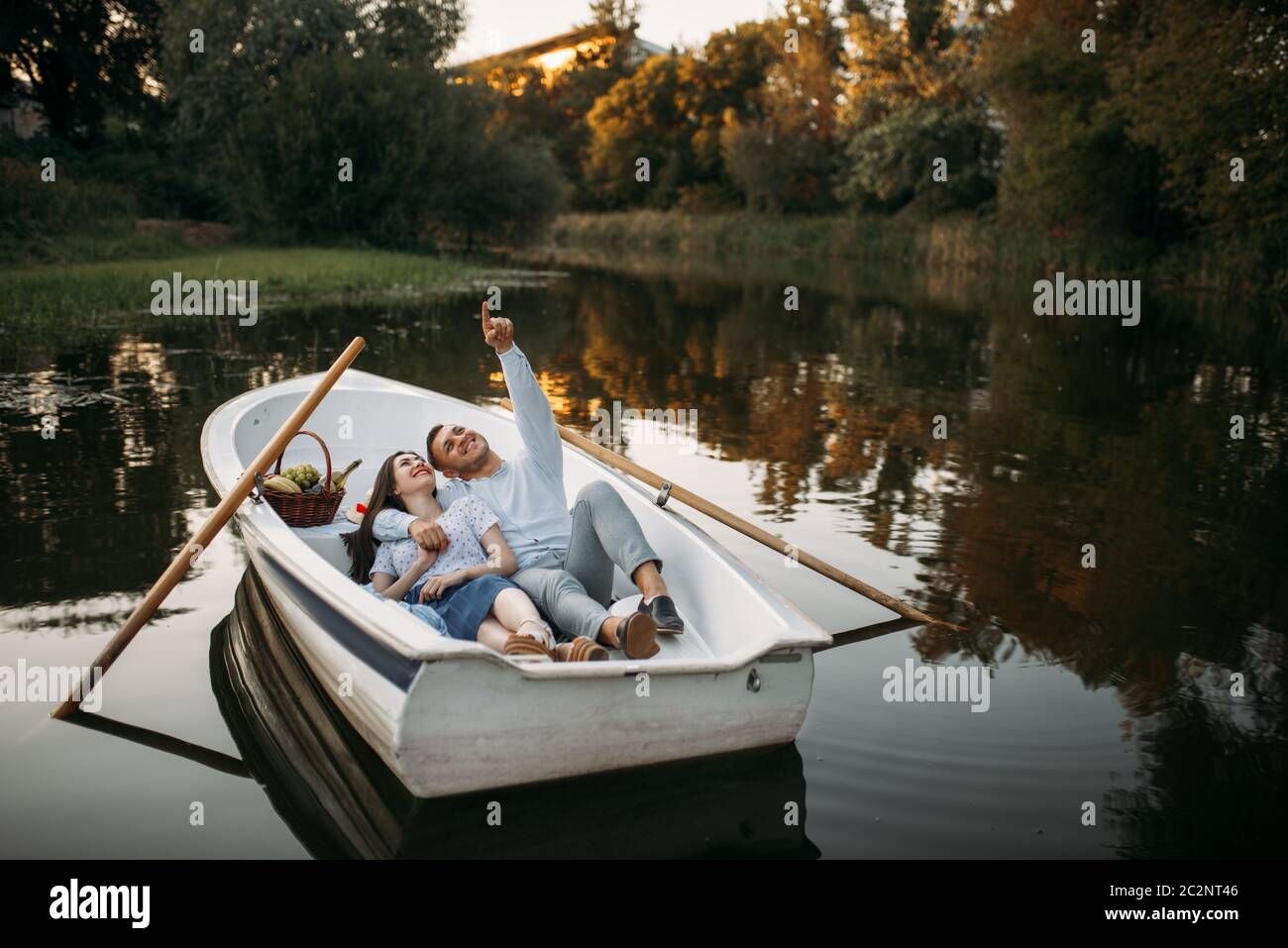 Love couple lying in a boat on quiet lake and dreaming at sunset ...