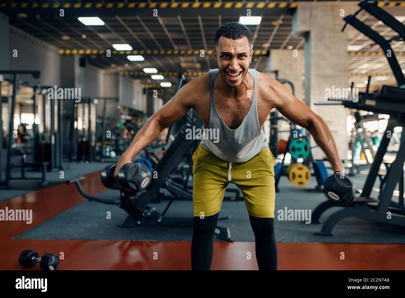 Muscular athlete in sportswear doing exercise with dumbbells on ...