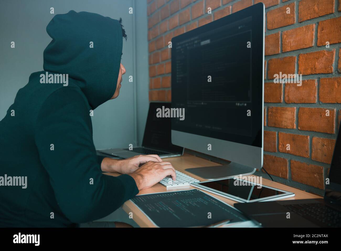 Hacker in the hood working with computer with hacking breaking into data servers Stock Photo - Alamy