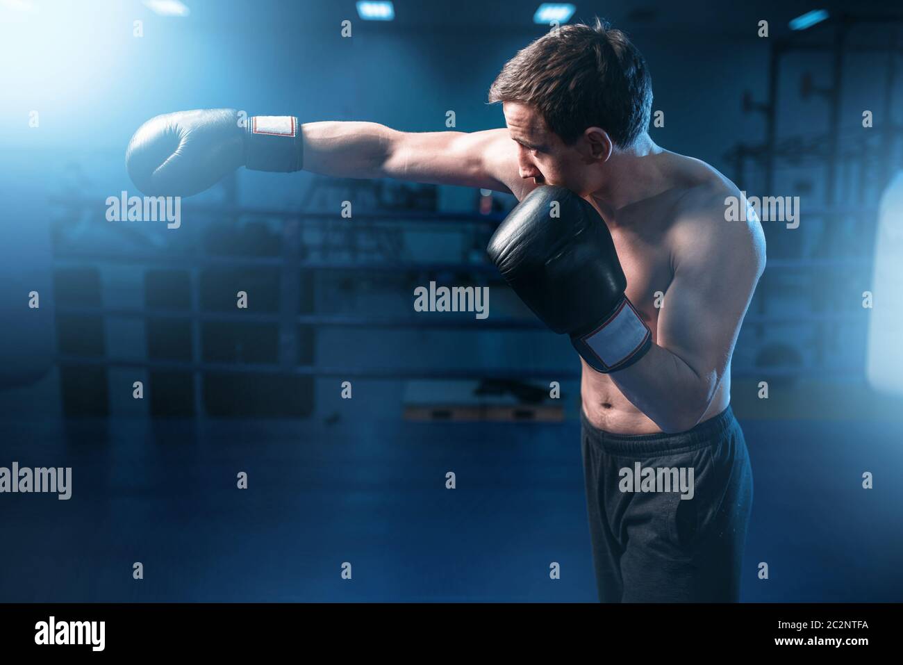 Muscular boxer in black gloves training in gym. Boxing workout, mens ...
