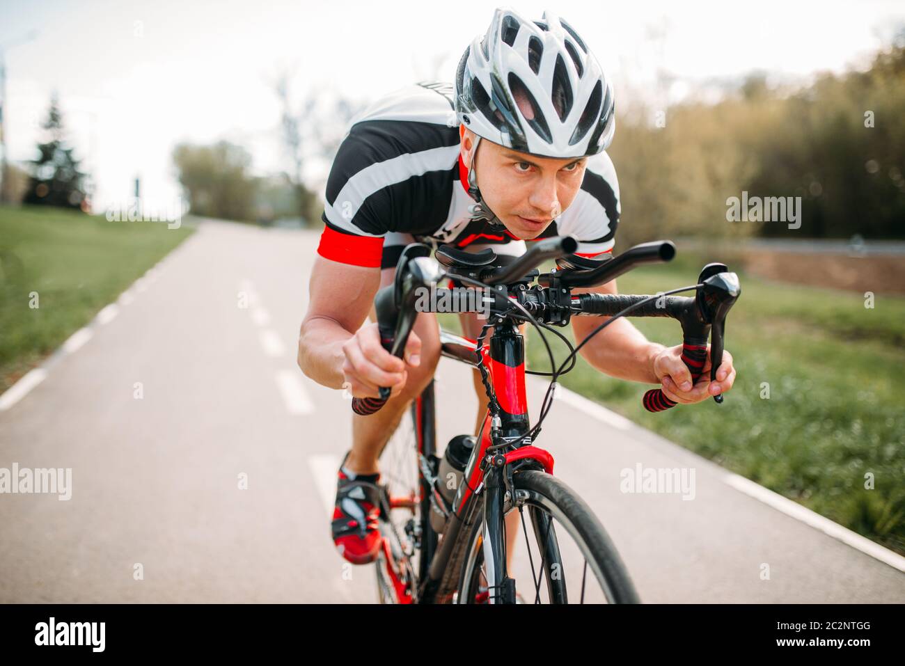 Male cyclist in helmet and sportswear rides on bicycle, front view ...