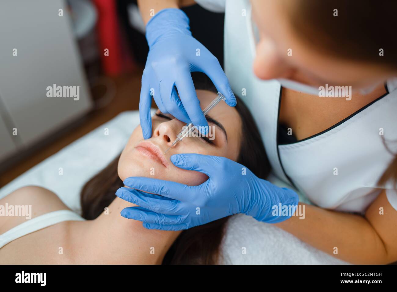 Cosmetician in gloves gives face botox injections to female patient on ...
