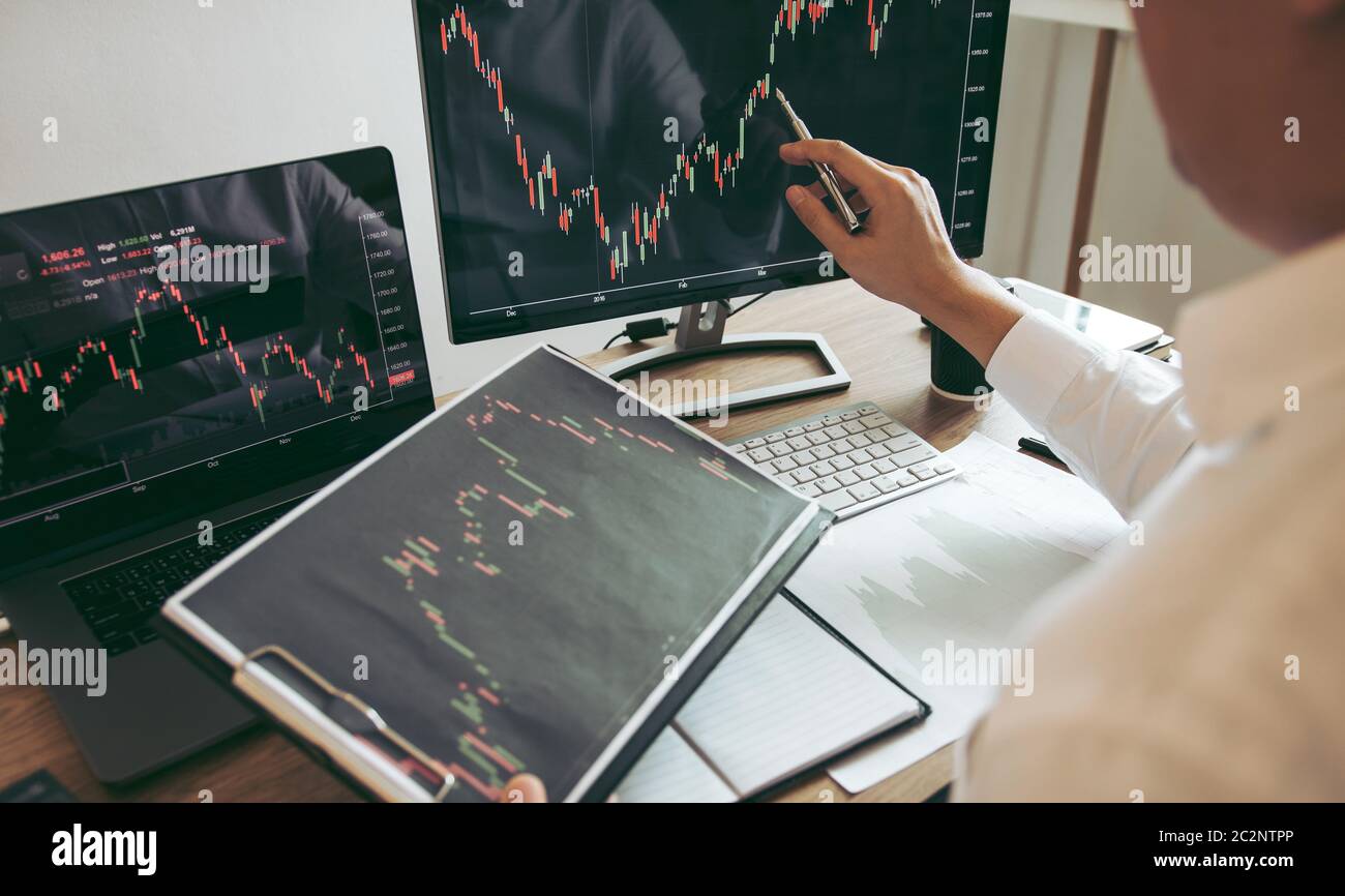 Investor man analyzing the graph of the stock market using a pen ...