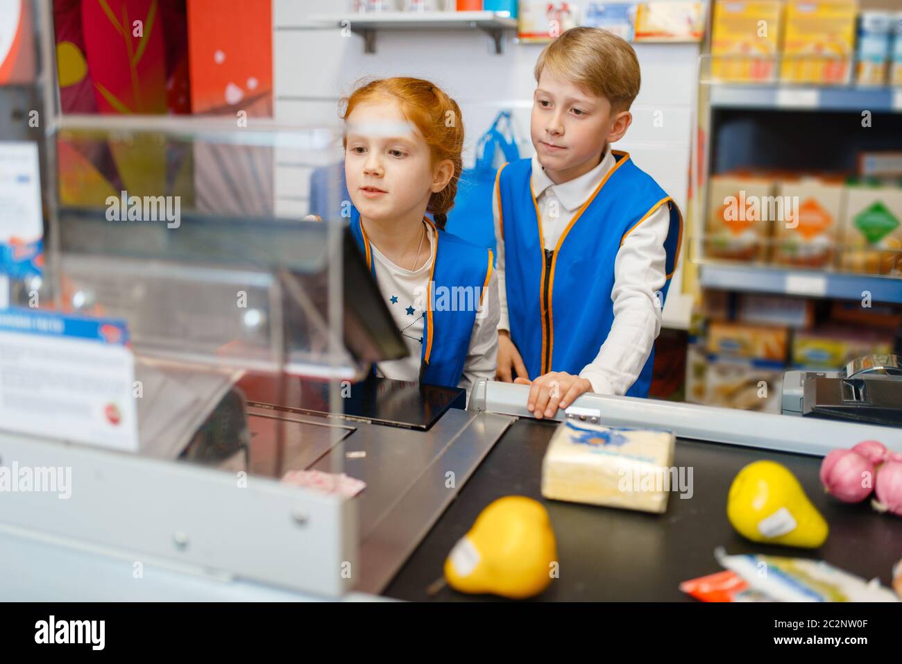 Girl and boy in uniform at the register playing saleswoman, playroom ...