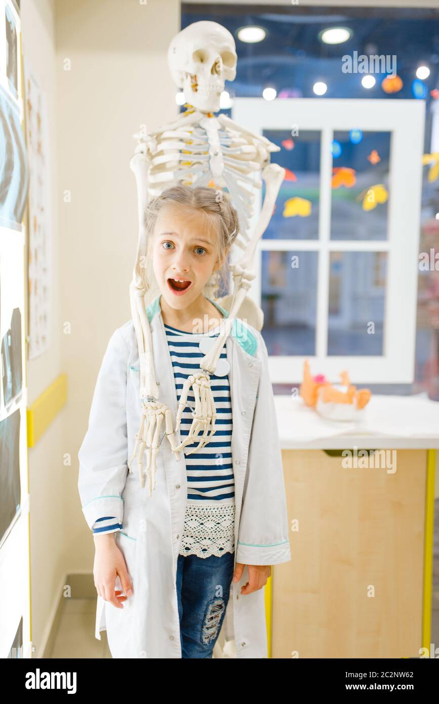 Little girl in uniform near a human skeleton, playing doctor, playroom ...