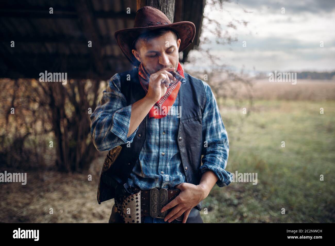Brutal cowboy smokes a cigar, texas ranch on background, western ...