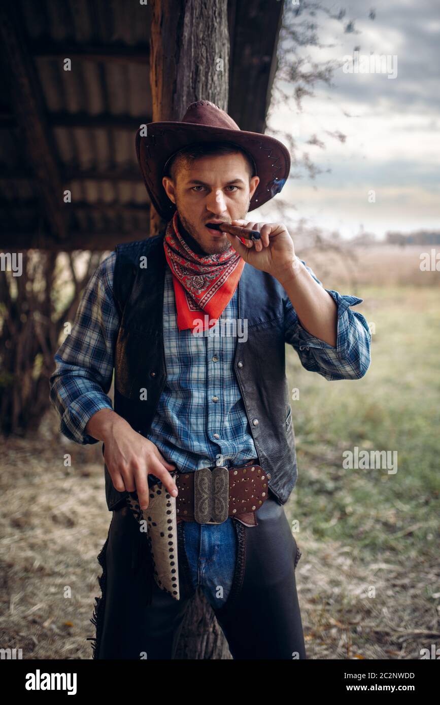 Brutal cowboy smokes a cigar, texas ranch on background, western ...