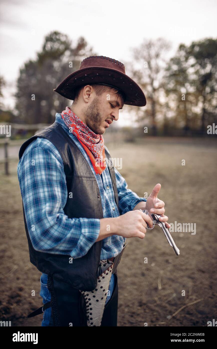 Cowboy checks his revolver before gunfight on ranch, western. Vintage ...