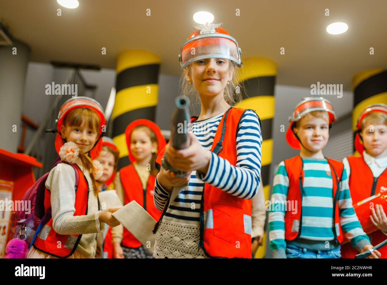 Child in helmet and uniform with hose in hands playing fireman ...