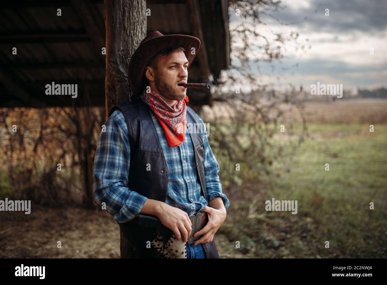 Brutal cowboy smokes a cigar, texas ranch on background, western ...