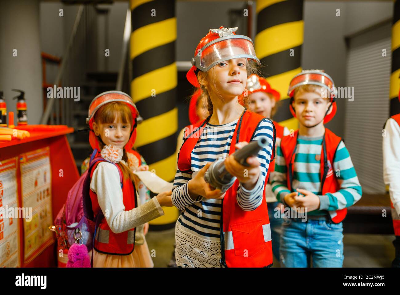 Child in helmet and uniform with hose in hands playing fireman ...