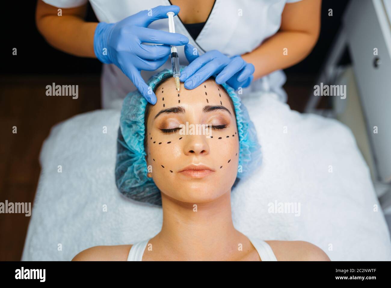 Cosmetician makes botox injection in dotted lines on female patient ...