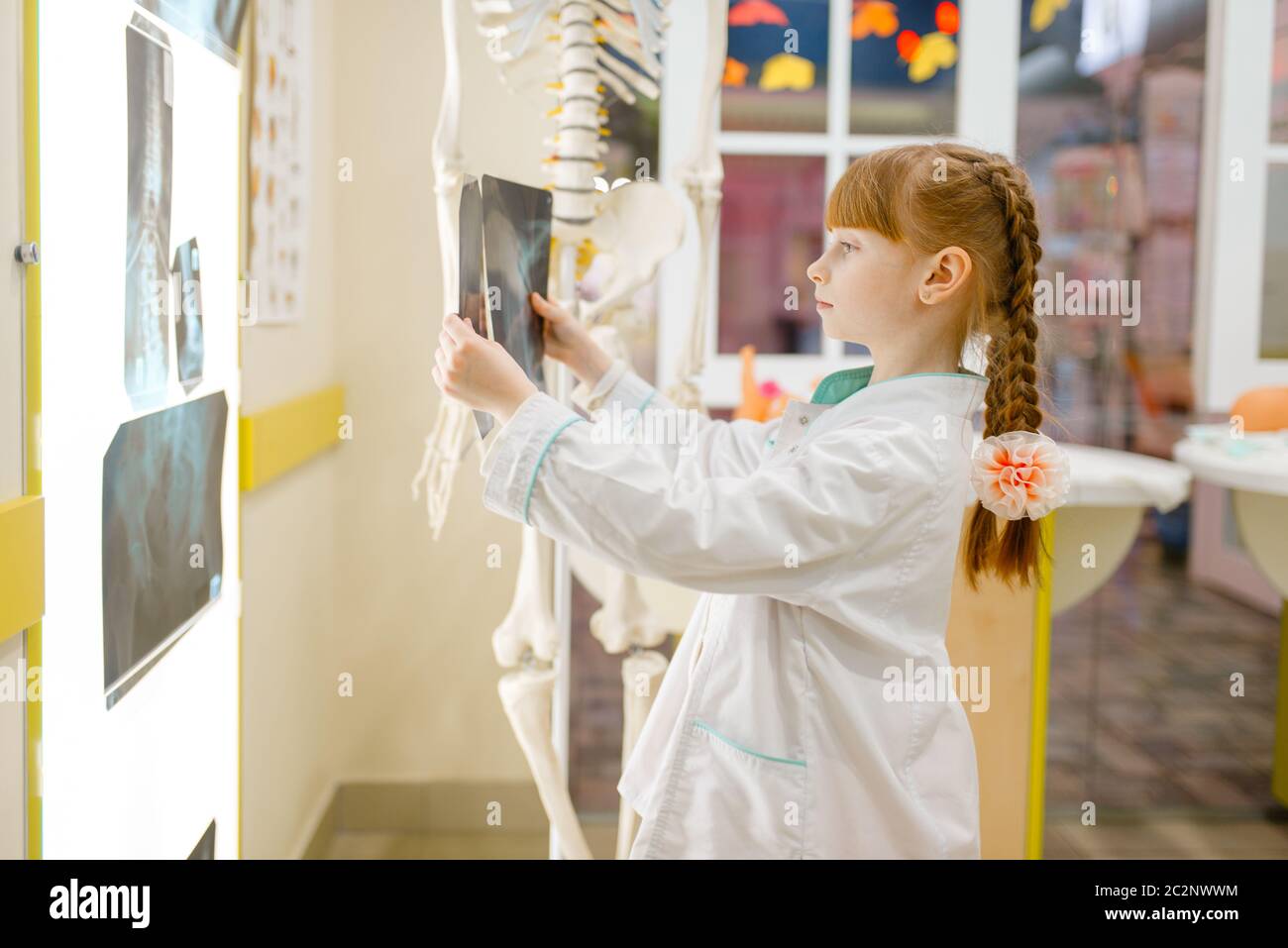 Little girl in uniform looks at the x-ray, playing doctor, playroom ...