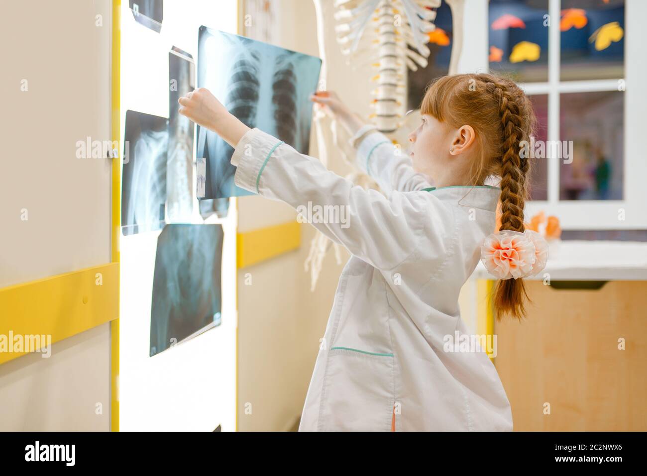 Little girl in uniform looks at the x-ray, playing doctor, playroom ...