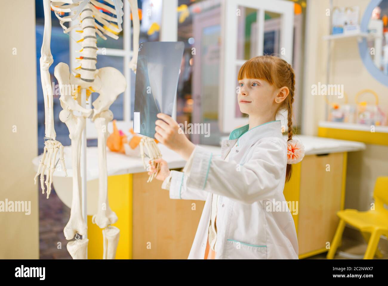 Little girl in uniform looks at the x-ray, playing doctor, playroom ...
