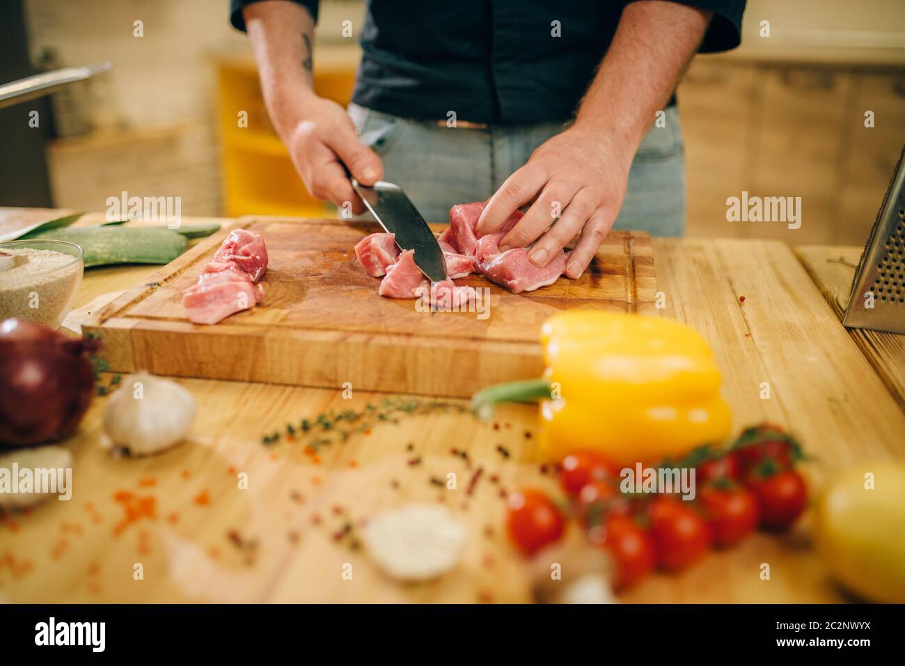 Male person hands with knife cuts raw meat into slices, top view ...