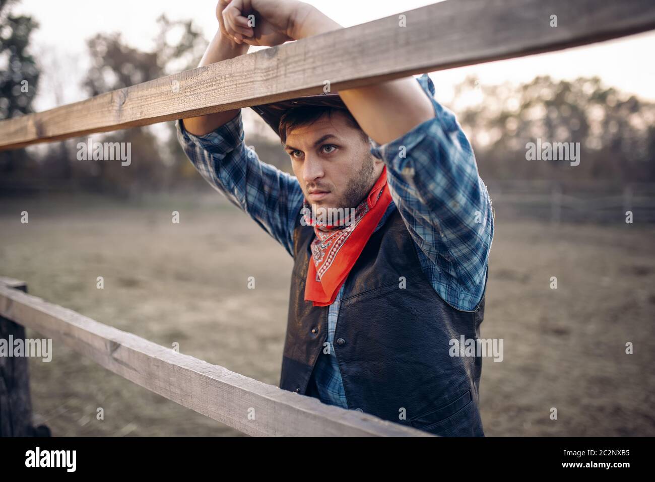 Young cowboy in leather jacket and hat poses on ranch, western. Vintage ...