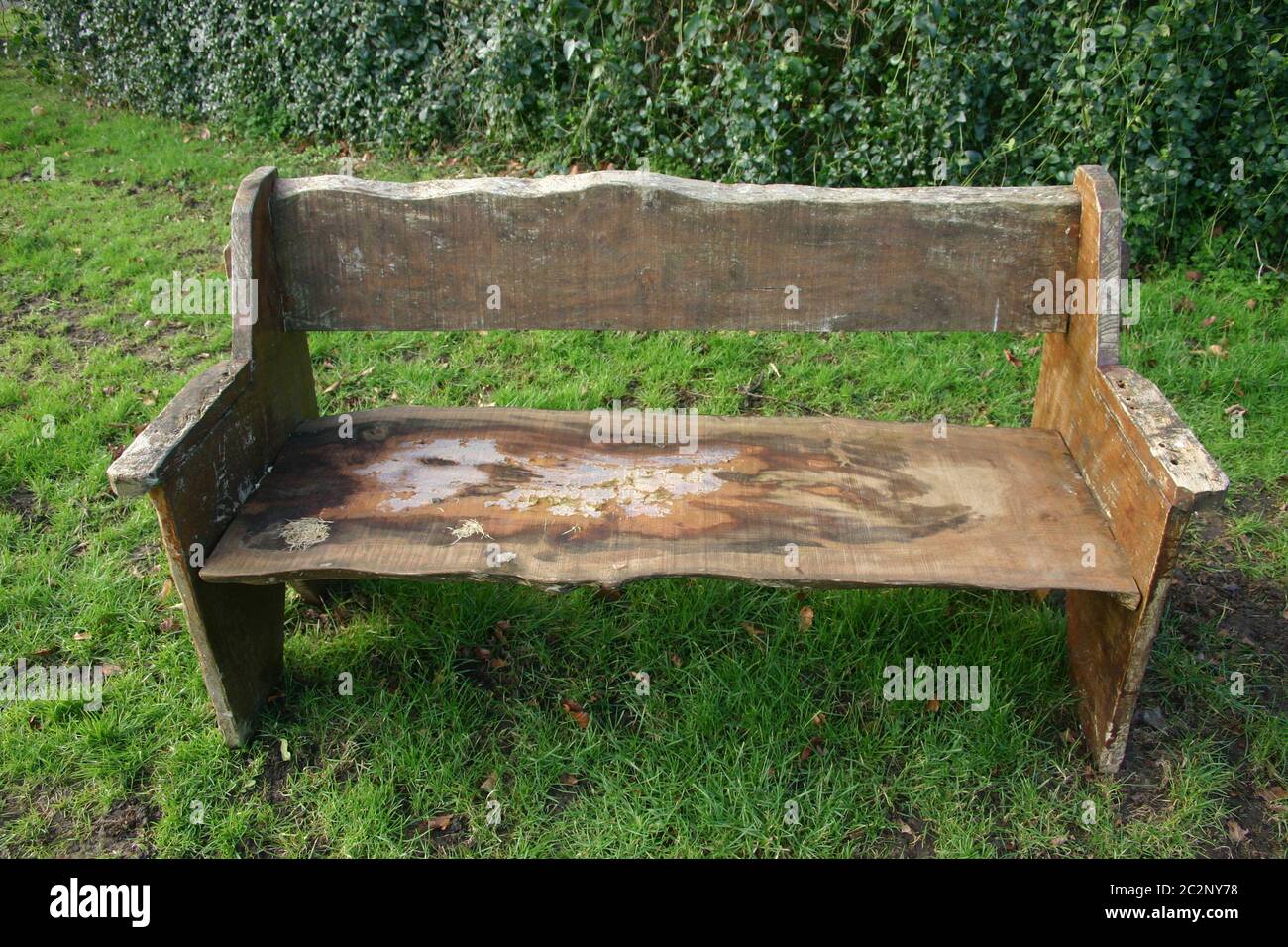 Rustic bench seat made from rough cut tree planks. The seat is worn ...