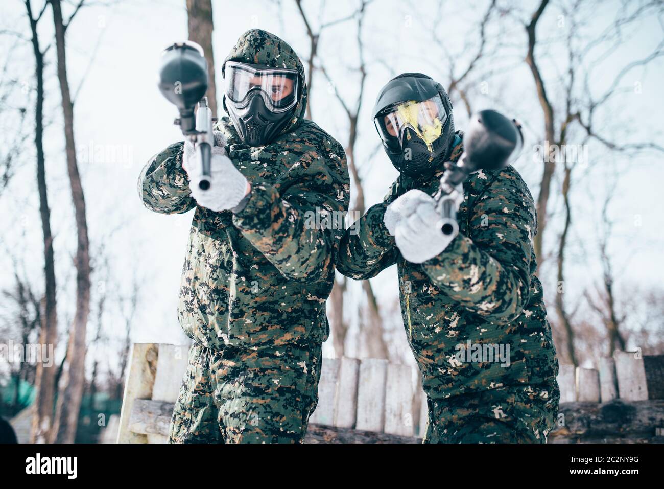 Two paintball players in splattered masks, team poses after winter ...