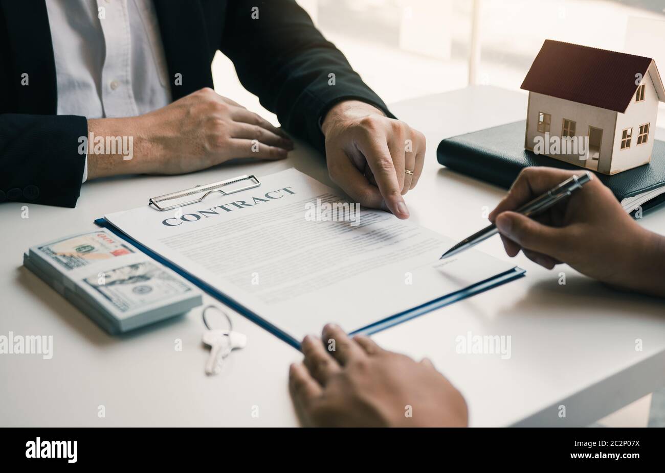 New home buyers are signing a home purchase contract at the agent's ...